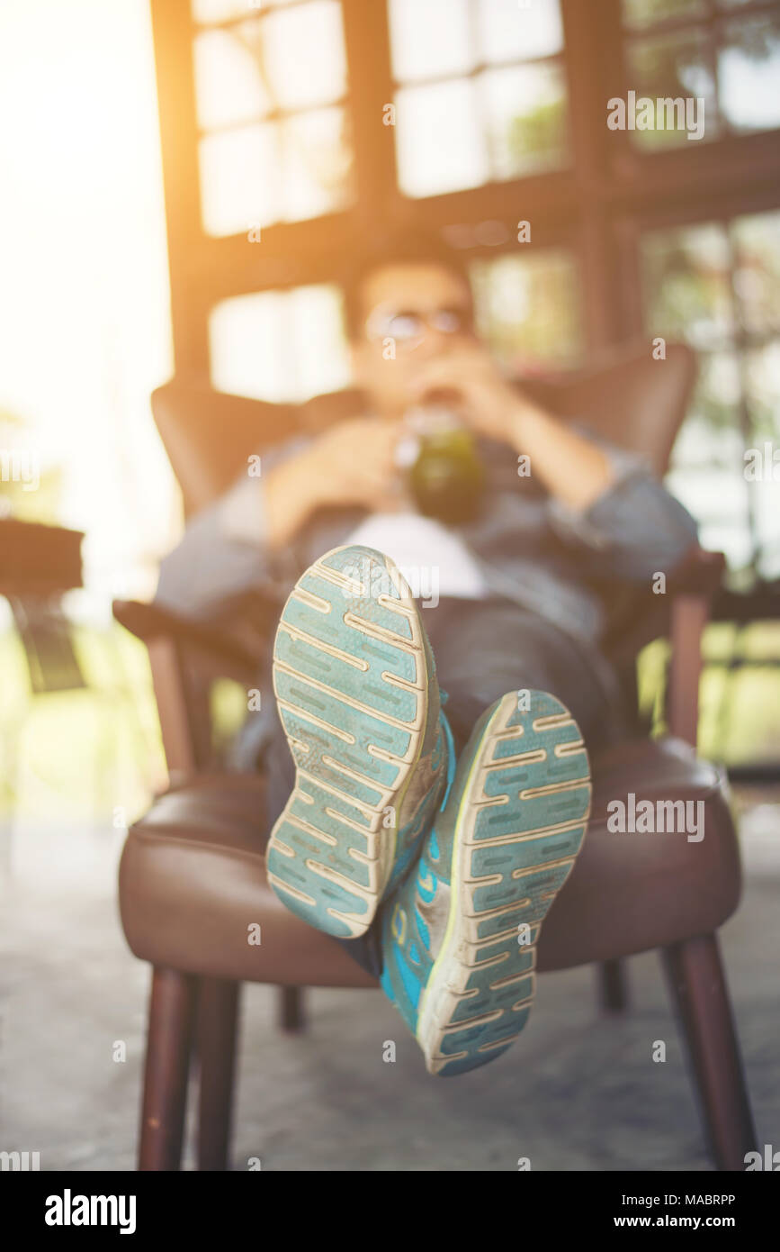 Low angle view of hipster resting with legs on sofa at home Stock Photo ...
