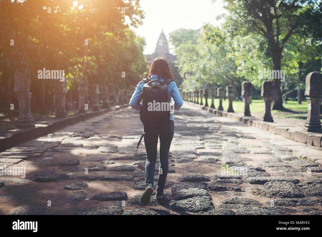 Rear view of young attractive woman tourist with backpack coming to ...
