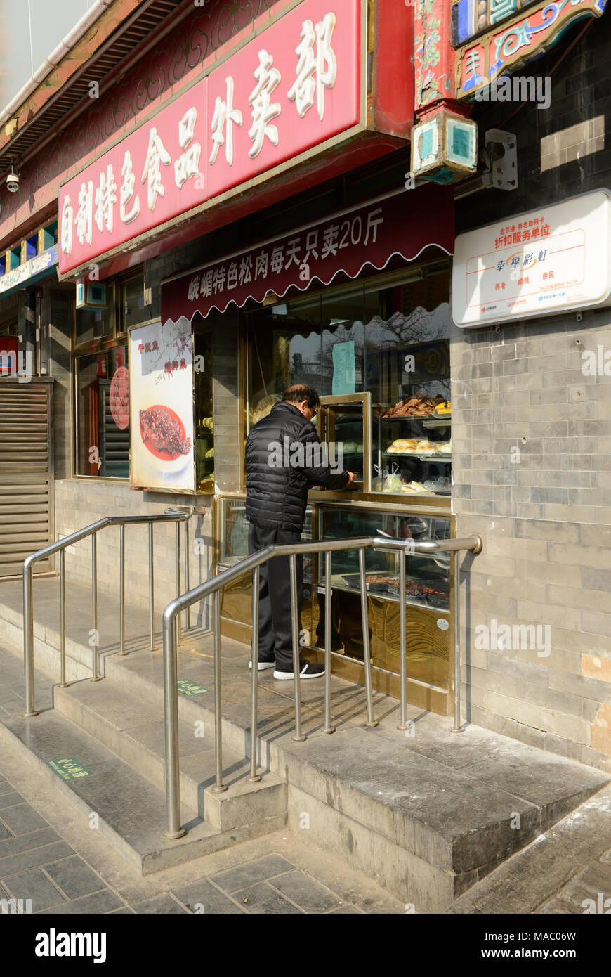 A man buys some pastries from the window of a cake shop and cafe in ...