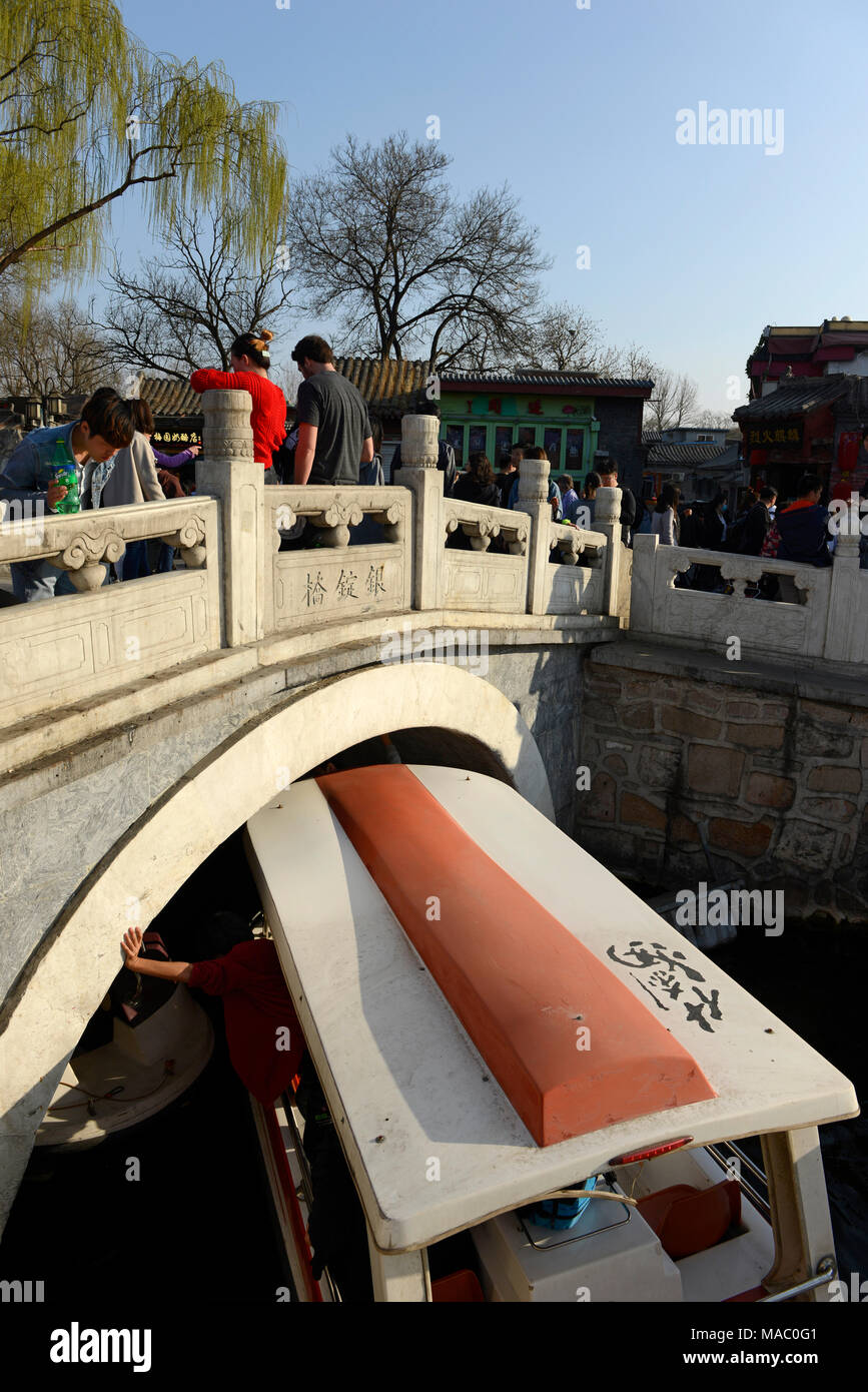 A tourist boat passes under a bridge at Houhai in north central Beijing ...