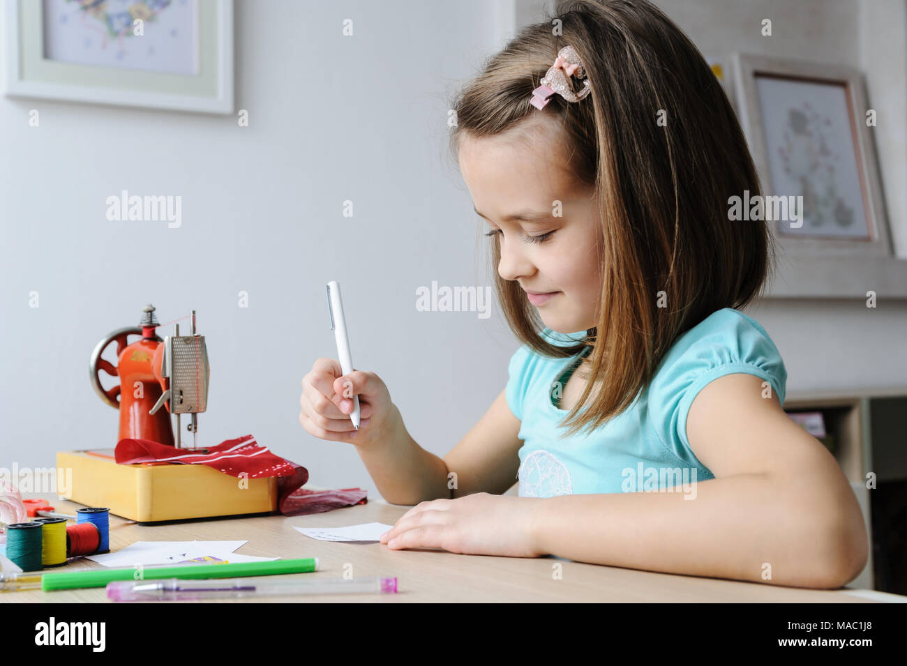 The girl is drawing a sketch of a dress for a doll. To sew it on a ...