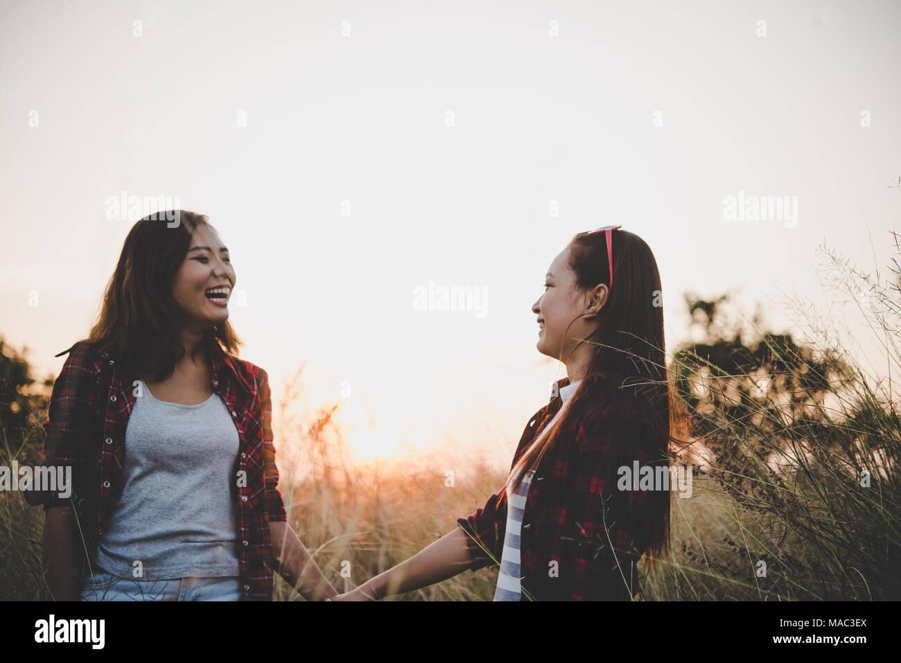 Close up of two girls. Close friends in field with sunset background ...
