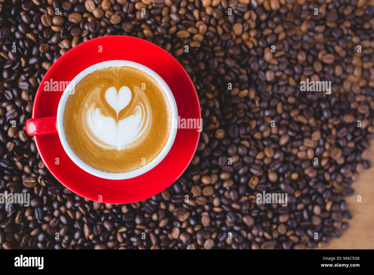 Latte art coffee above at coffee beans background Stock Photo - Alamy
