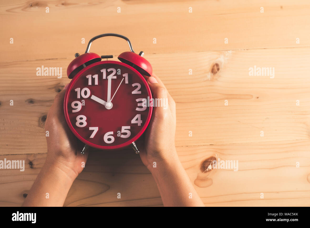 Woman's hand with red alarm clock Stock Photo - Alamy