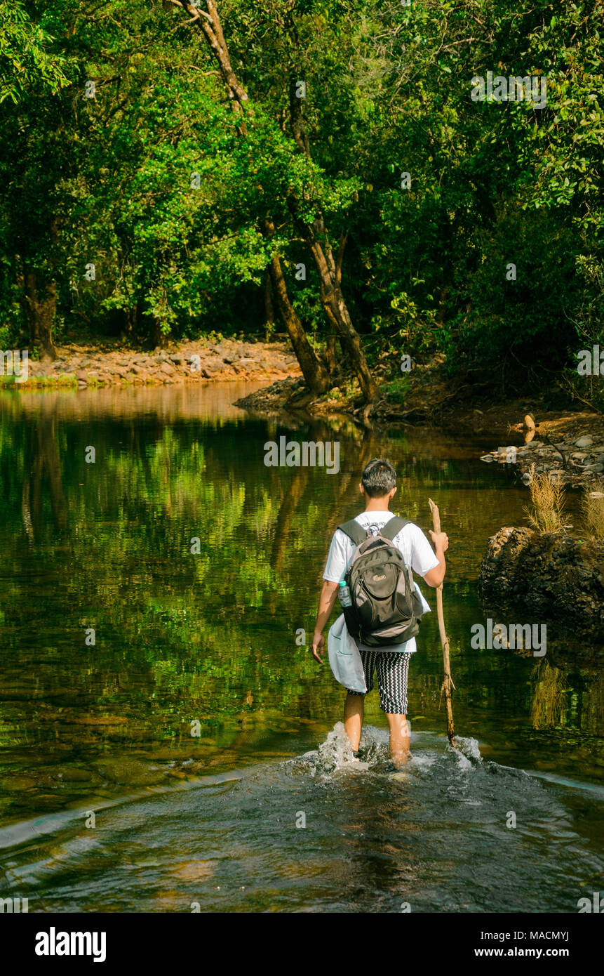 A boy wades through calm waters, destroying the reflections bit by bit ...