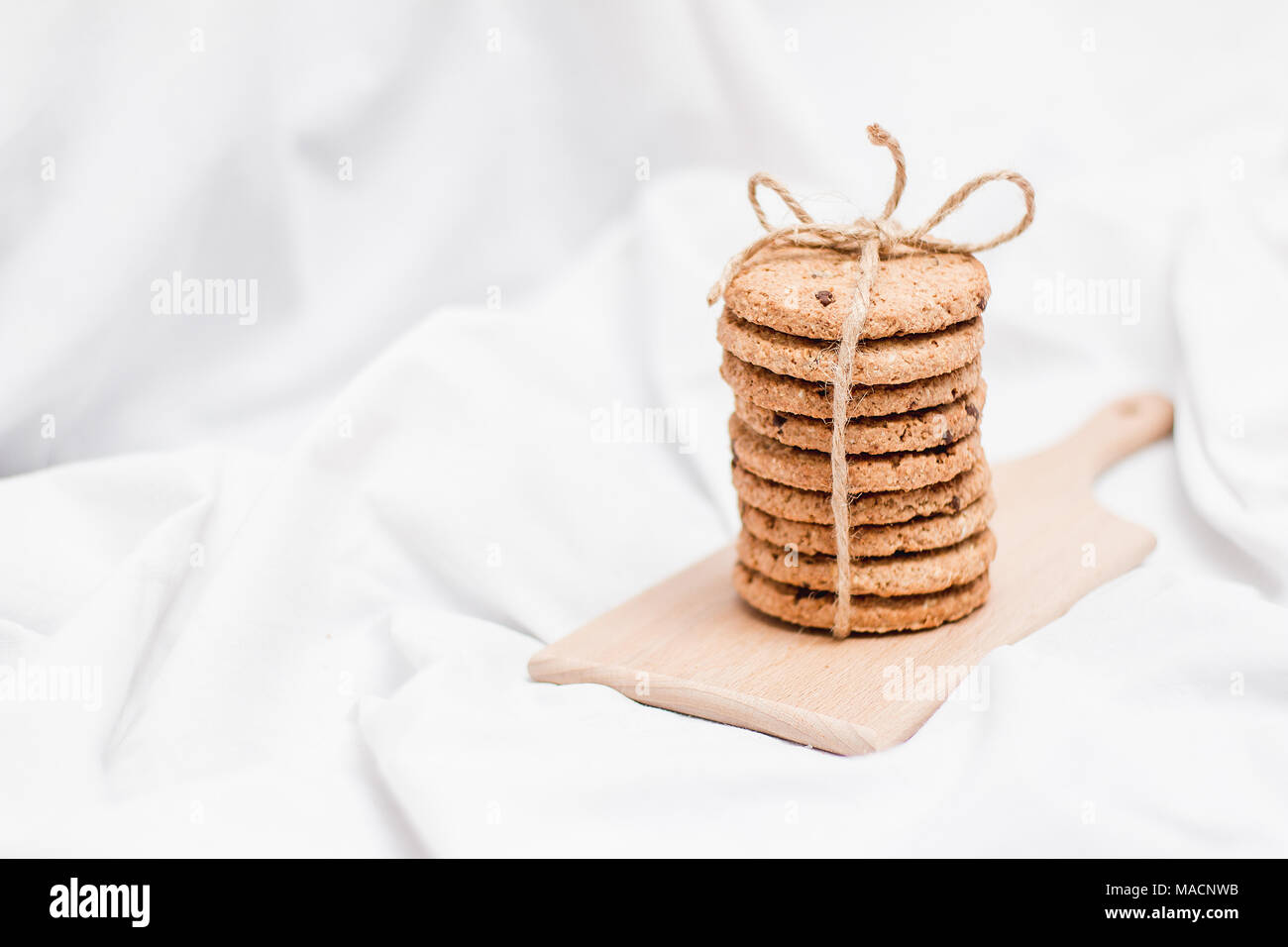Sweet homemade cookies wrapped with rope on a wooden board and white ...
