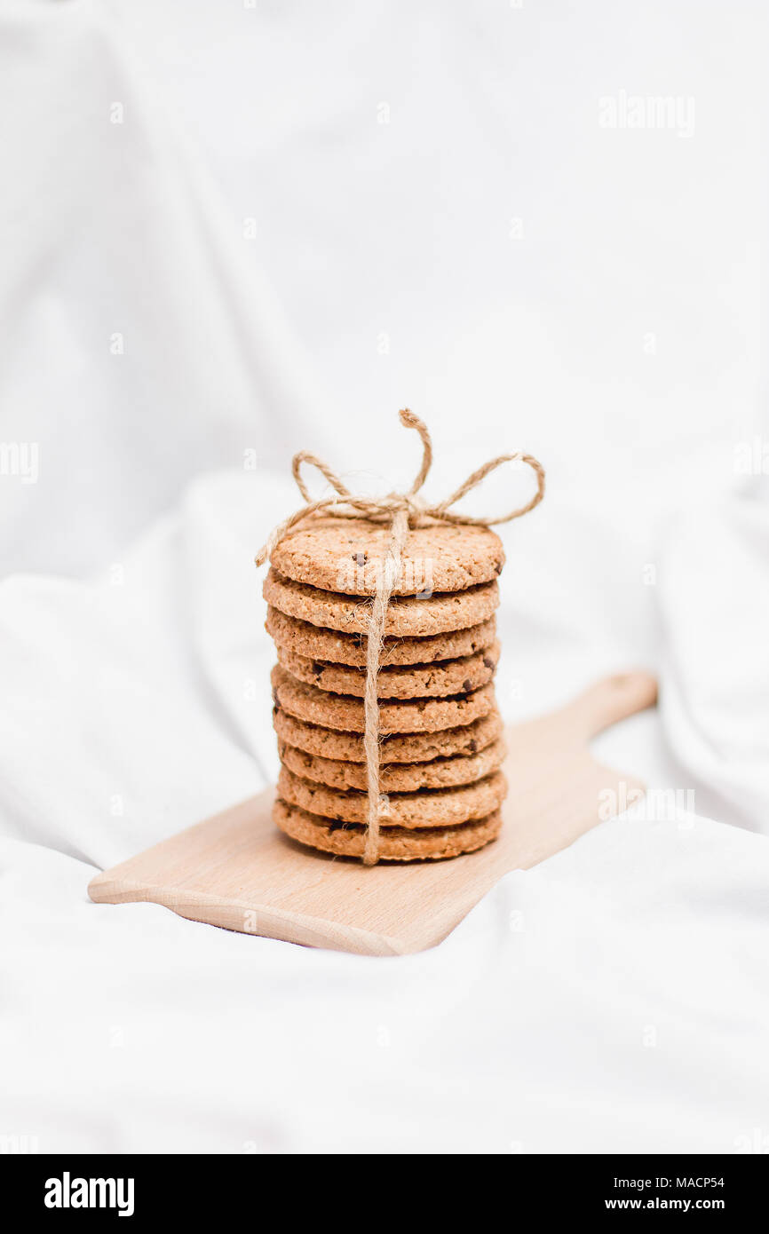 Sweet homemade cookies wrapped with rope on a wooden board and white ...