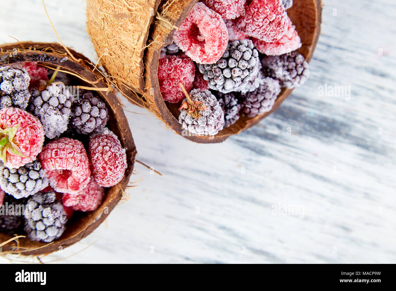 Frozen black and red raspberries in coconut bowl Stock Photo - Alamy