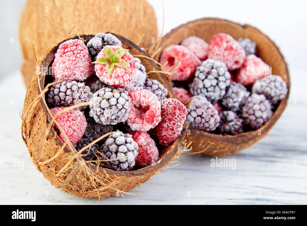 Frozen black and red raspberries in coconut bowl Stock Photo - Alamy