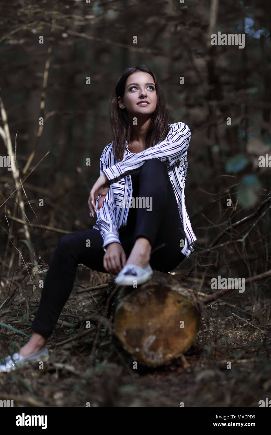 beautiful young woman sitting on a log Stock Photo - Alamy