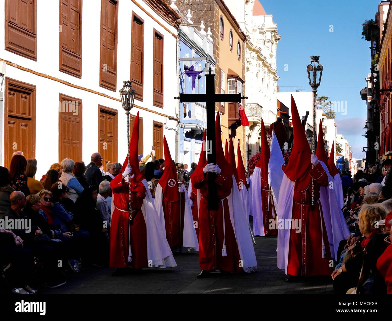 Penitents in red & white robes carrying cross walking solemnly in "La ...