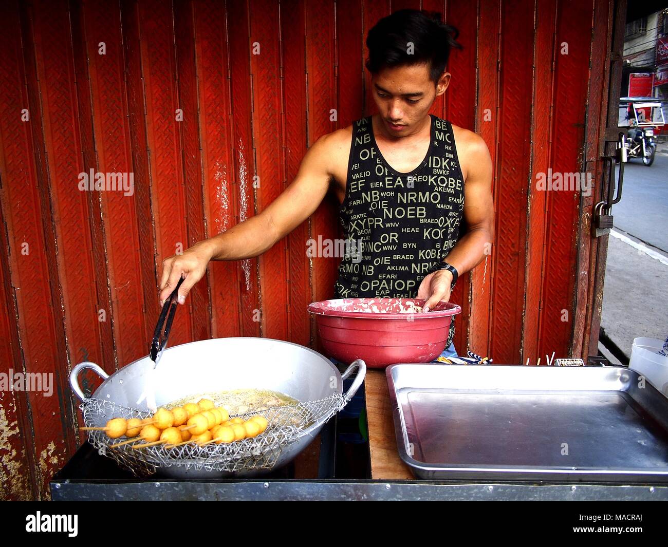 ANTIPOLO CITY, PHILIPPINES - MARCH 29, 2018: A street vendor deep fries ...