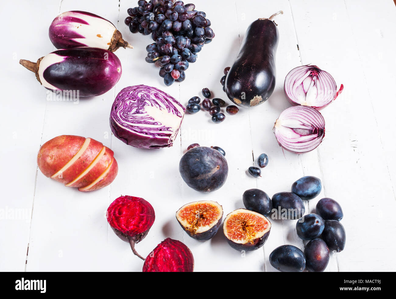 Collection of fresh purple fruit and vegetables on wooden background ...