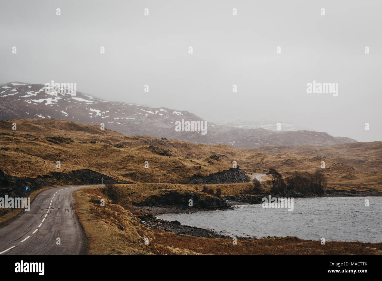 A road going through Scottish Highlands near Lochinver on a foggy ...