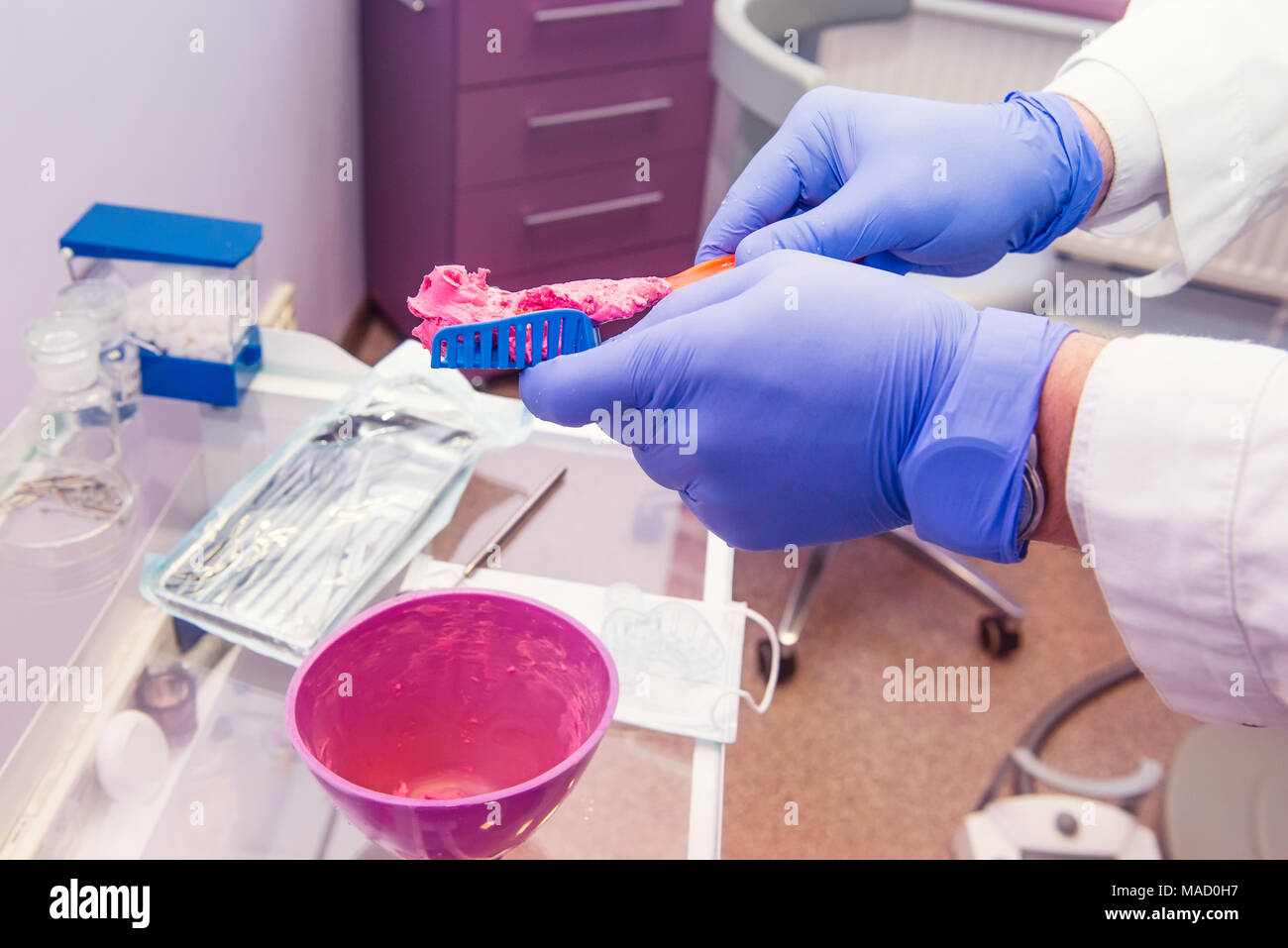 Close view of dentist's hands holding a model of jaws and put solution ...