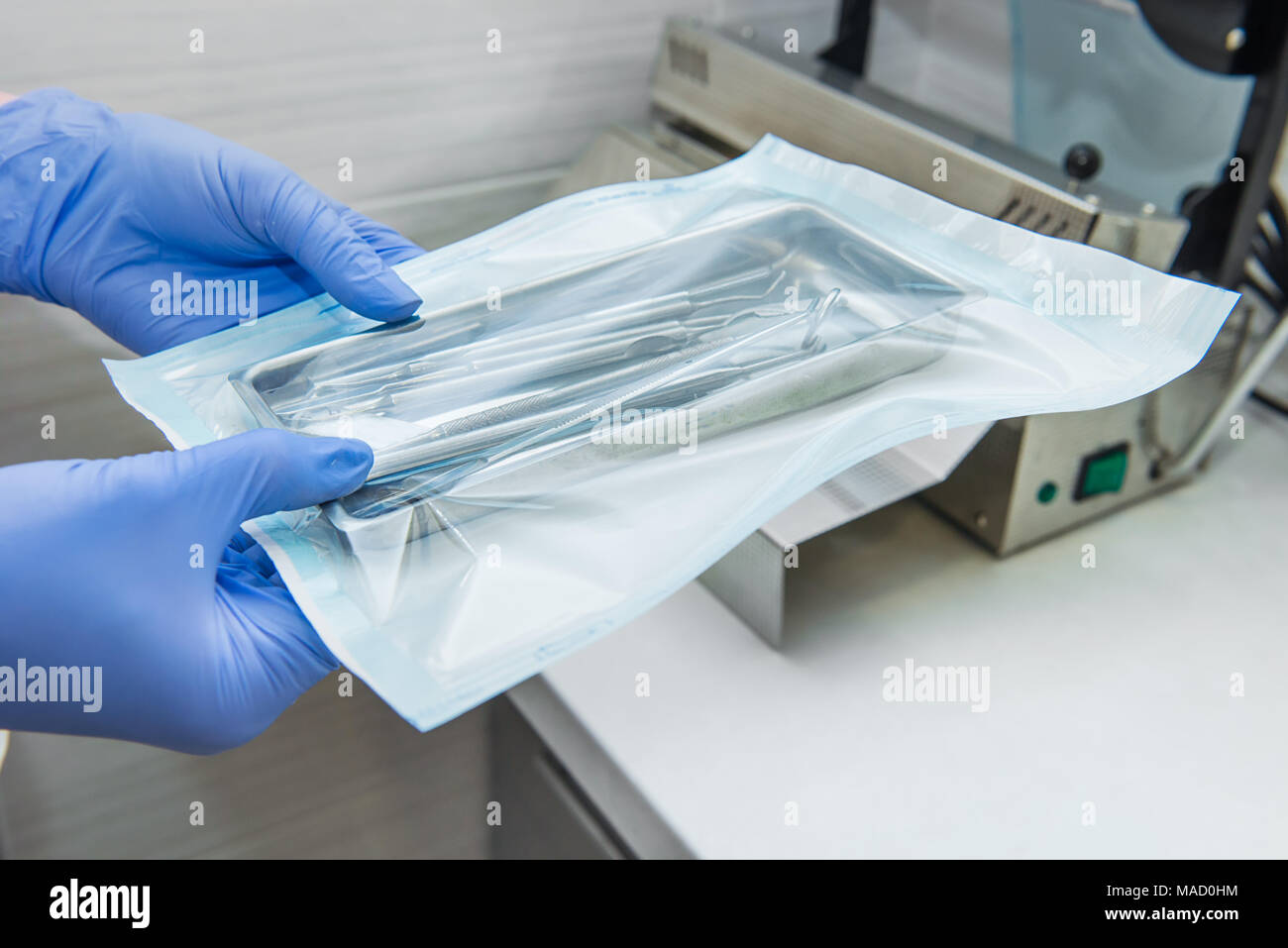 Close up dentist assistant's hands holding packaged with vacuum packing ...