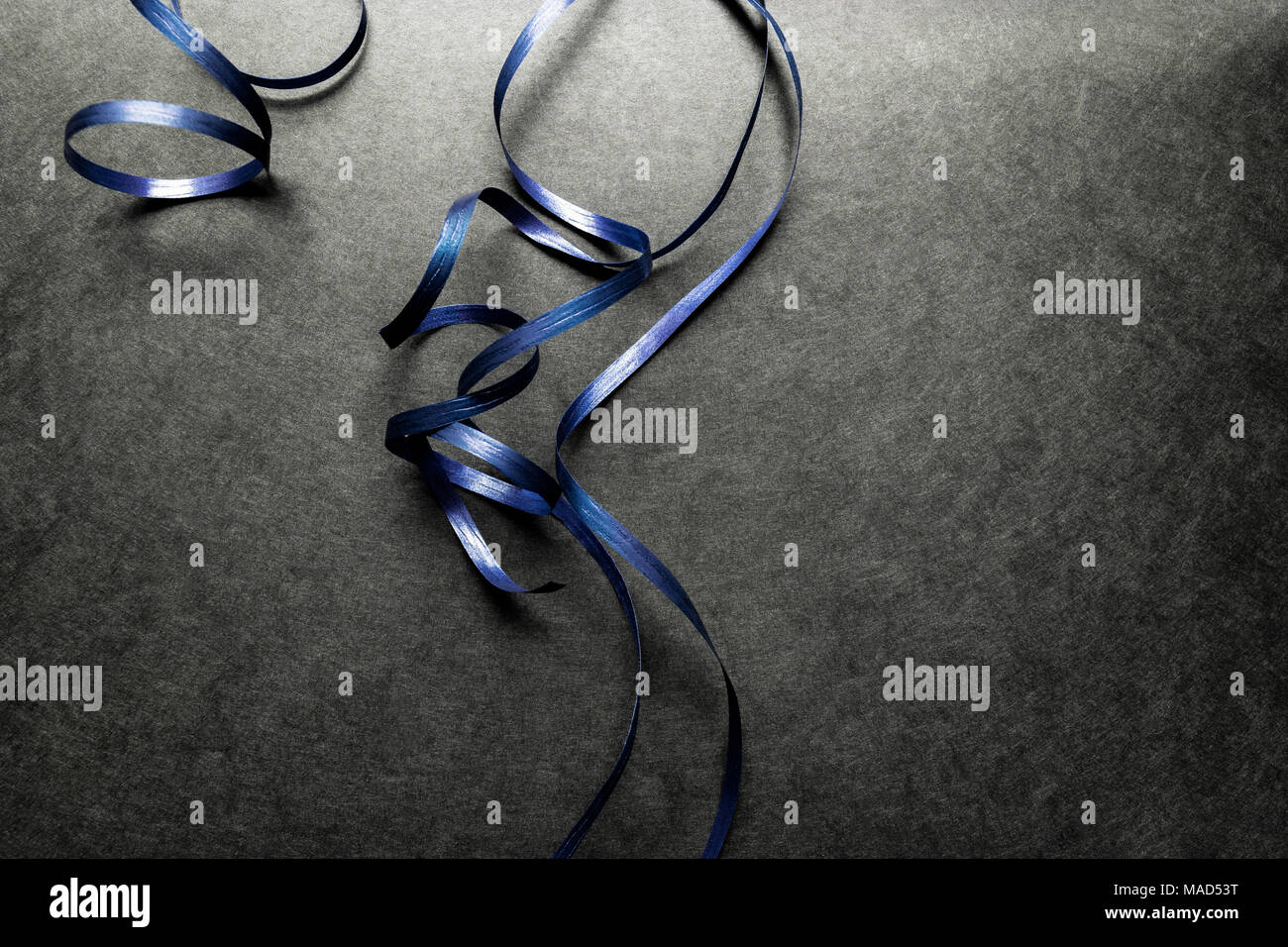 Blue wrapping ribbon placed on black surface background Stock Photo - Alamy