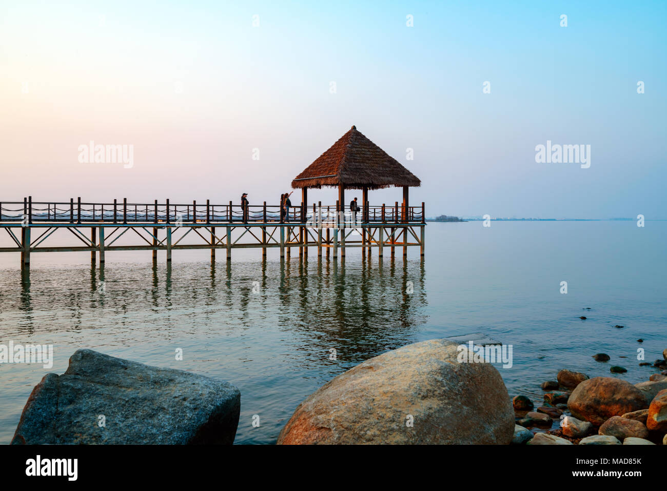 Tranquil lake and wooden trestle, dusk landscape Stock Photo - Alamy