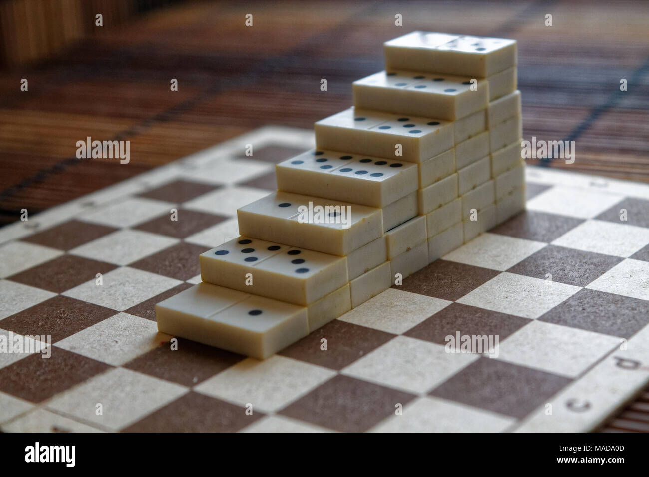 Pyramid of domino pieces on the bamboo brown wooden table background ...