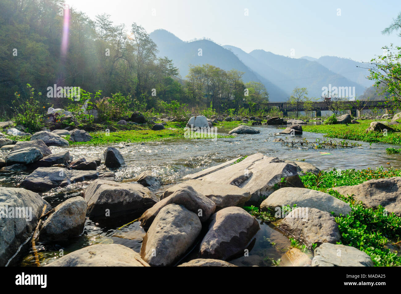 Smooth round rocks or boulders on a riverbank with grass and hills in ...