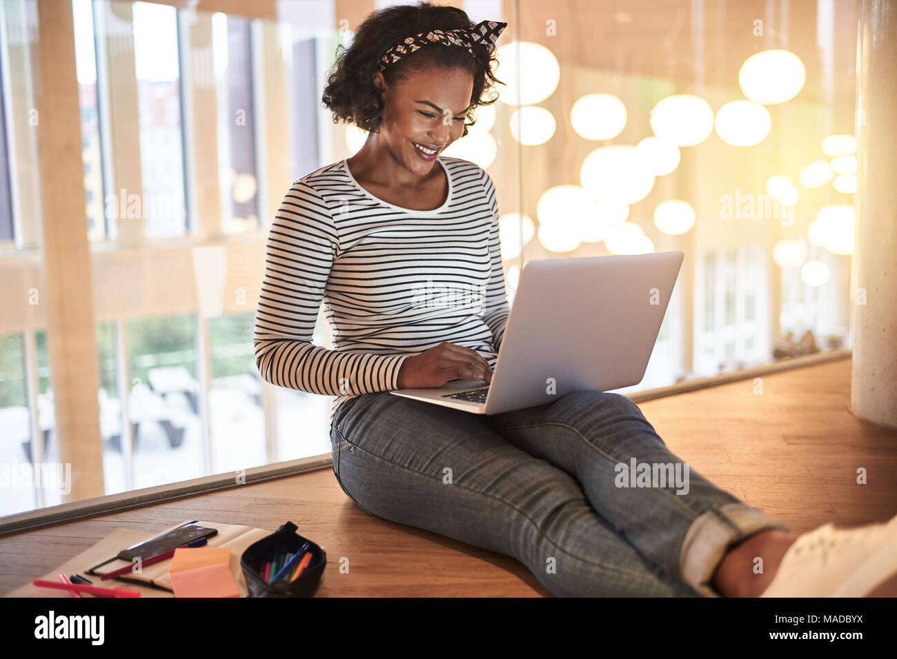 Smiling young African university student working with a laptop while ...