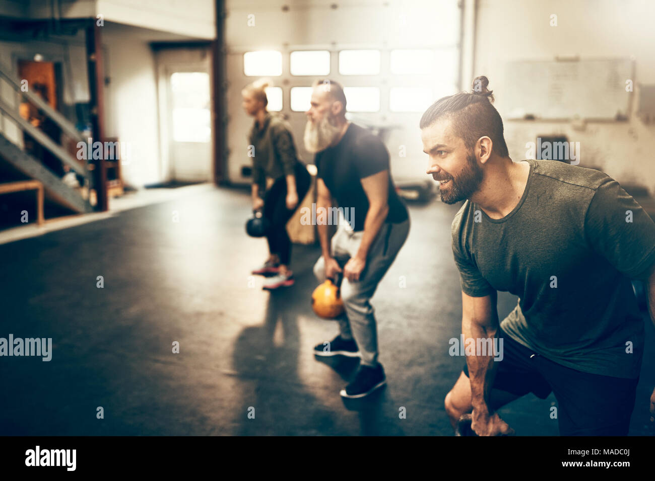 Fit group of people working out with dumbbells together during an ...