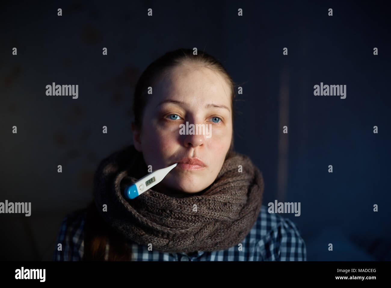 a young woman measures the temperature with an electronic thermometer ...