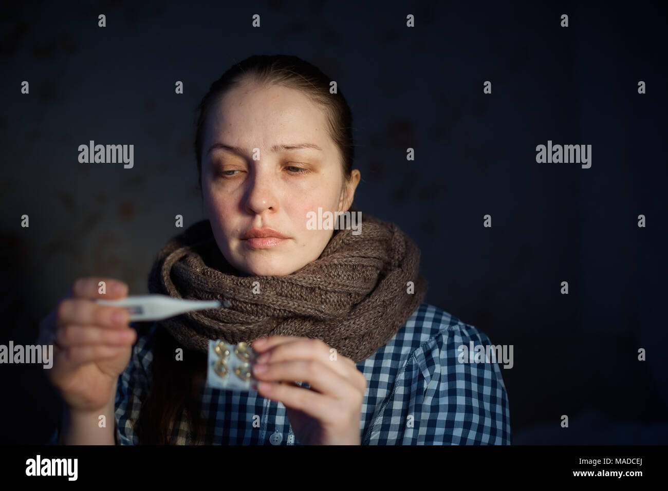 a young woman measures the temperature with an electronic thermometer ...