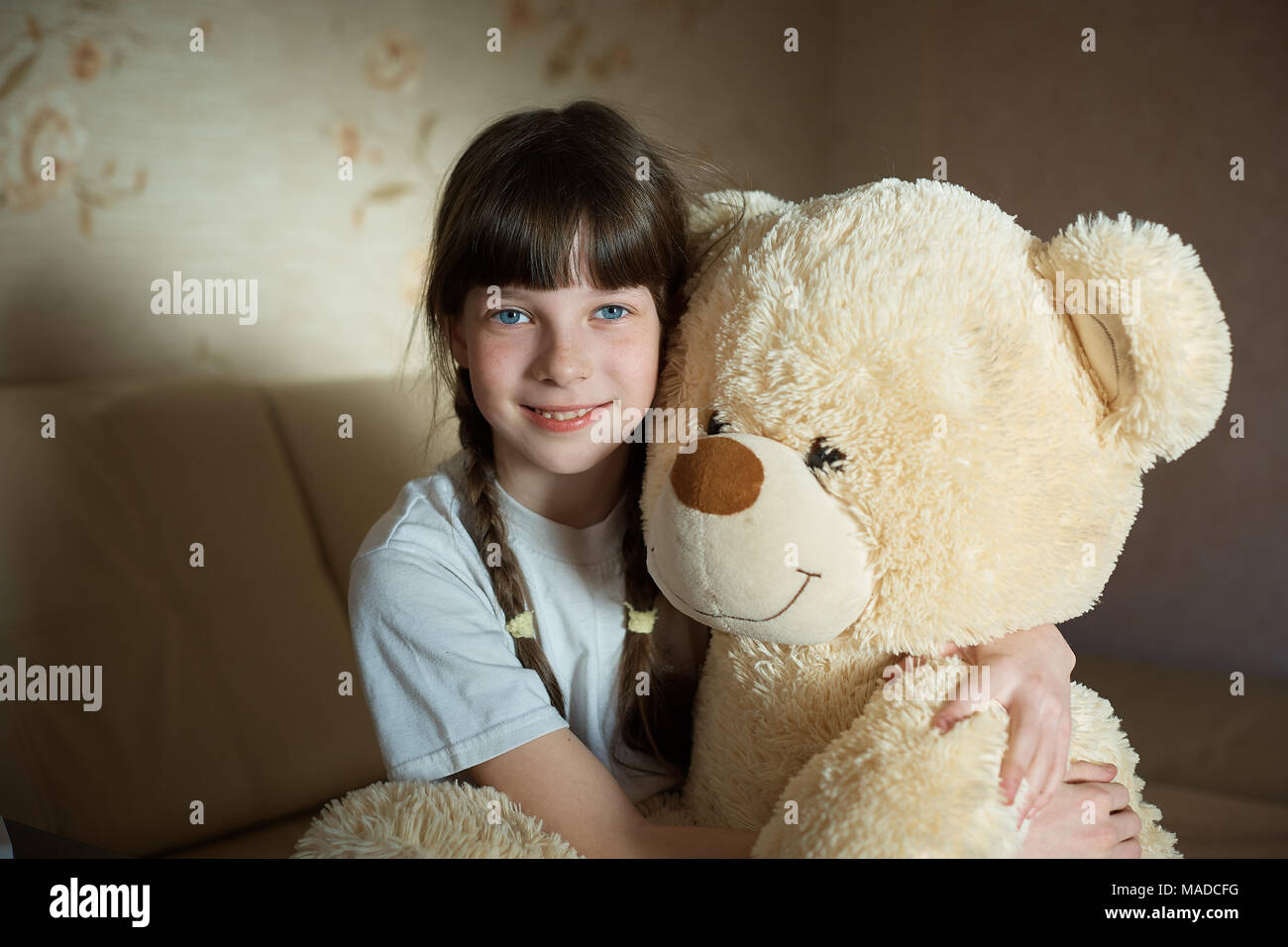 little girl hugging teddy bear indoor in her room, devotion concept ...