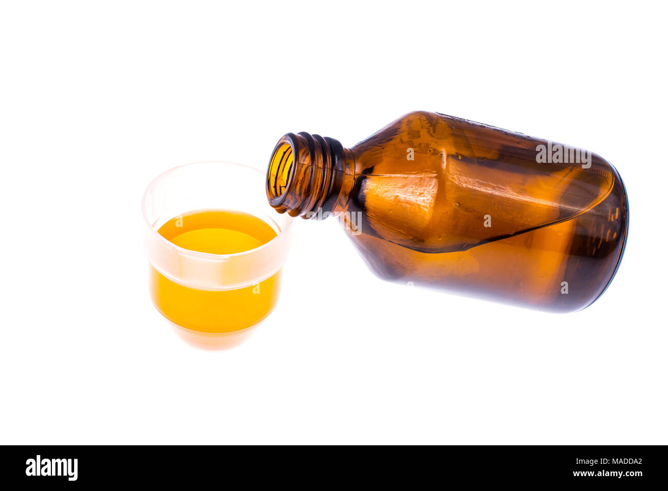 Medical bottle and measuring plastic cup with medicinal syrup on white ...