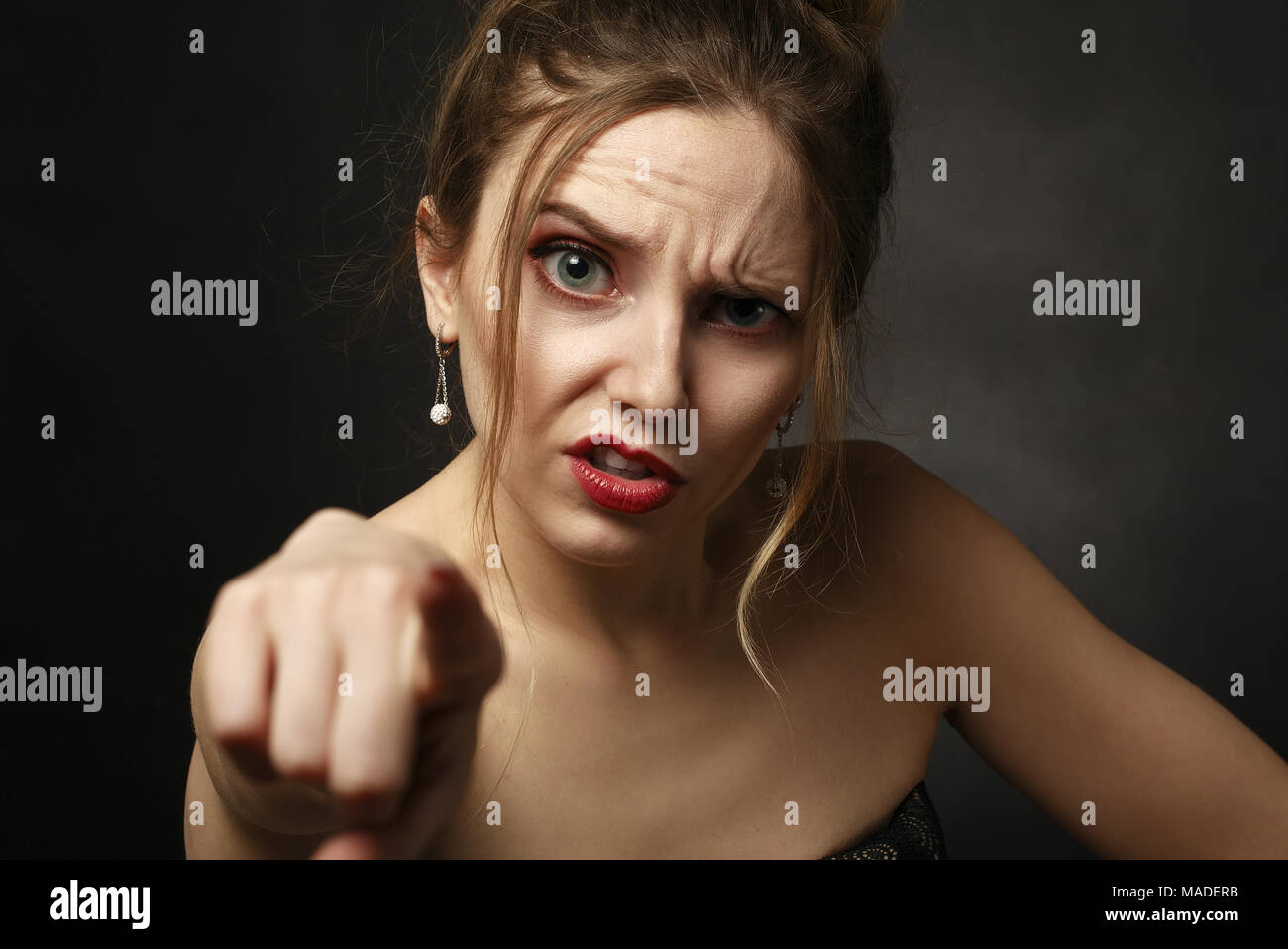 angry young woman on black background point on camera Stock Photo - Alamy