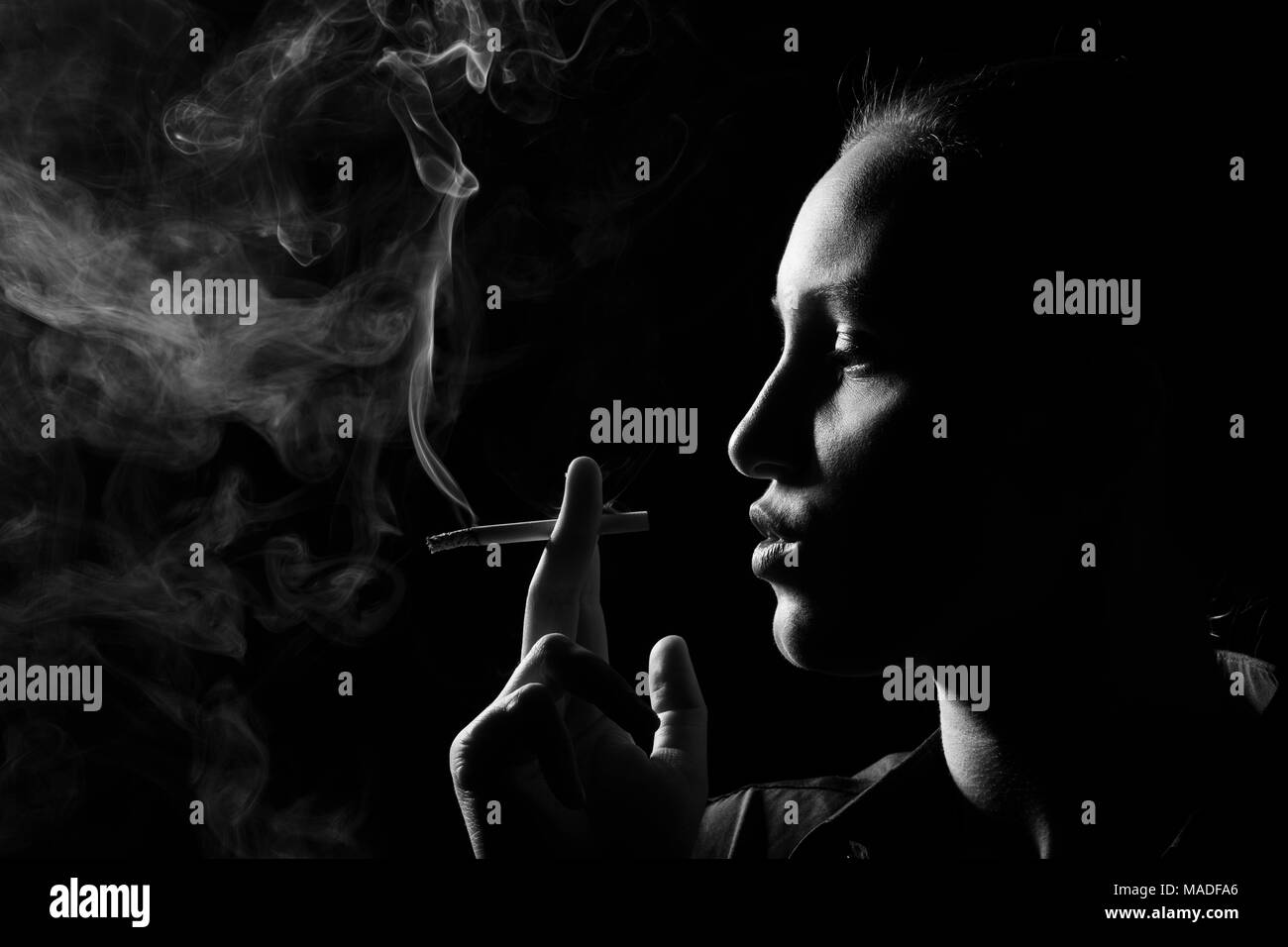 serious woman smoking cigarette on black background, profile view ...