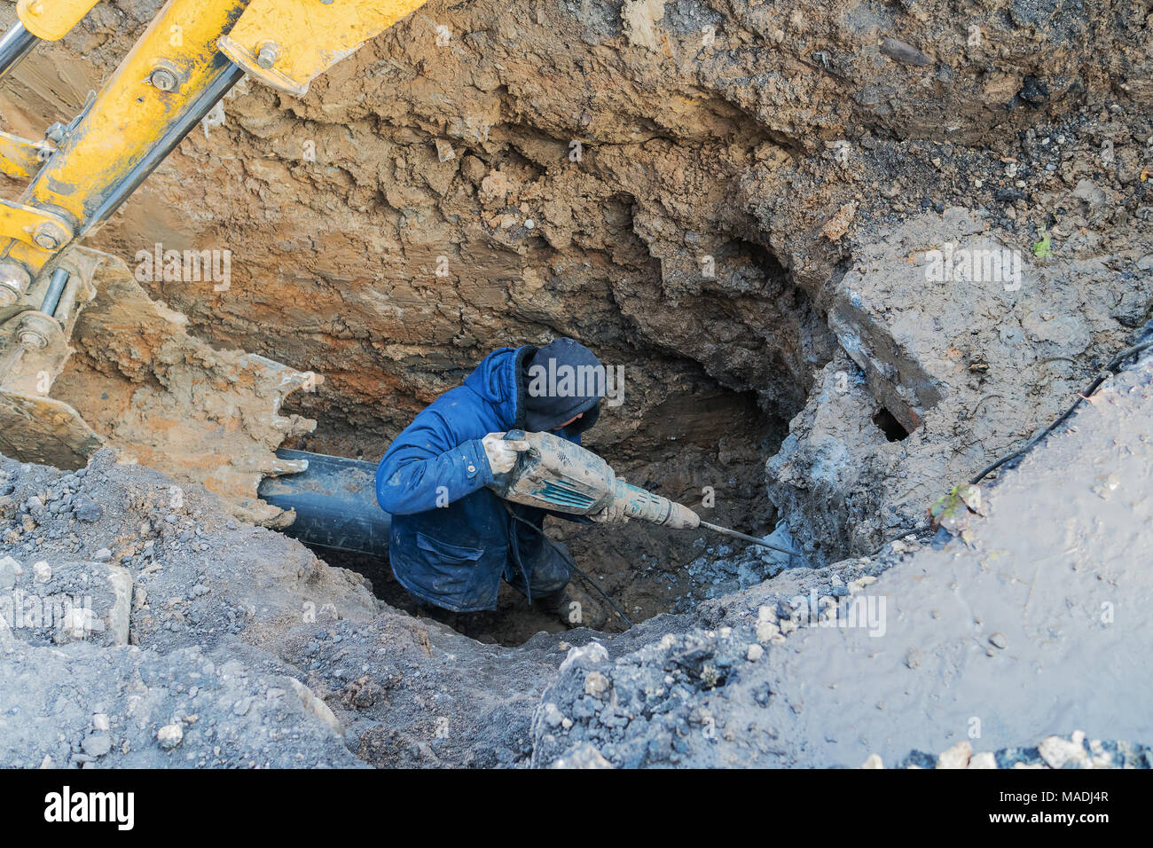 Workers excavate the pit with an excavator. Road repair. Pipeline ...