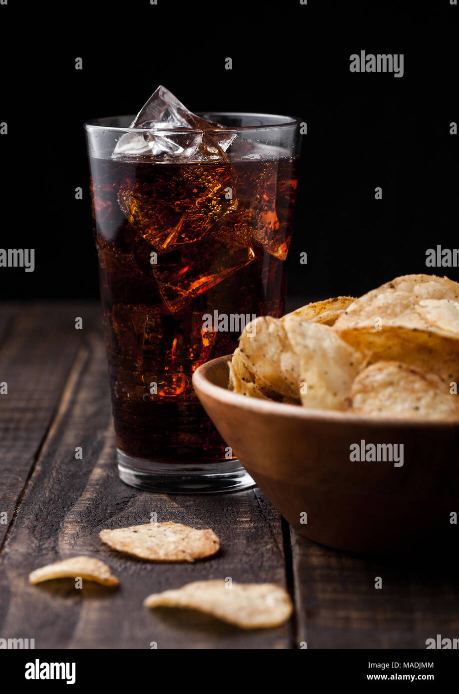 Crispy pepper crisps in wooden bowl with cola soda on wooden background ...