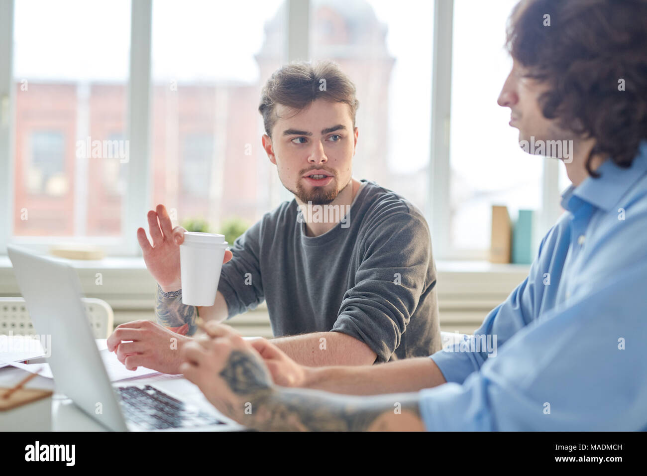 Two business colleagues having a conversation at the table and drinking ...