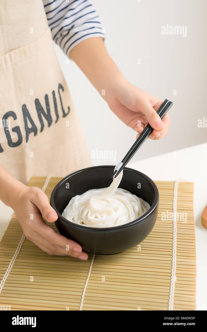 Female chef prepare traditional Vietnamese soup Pho bo with herbs, meat ...