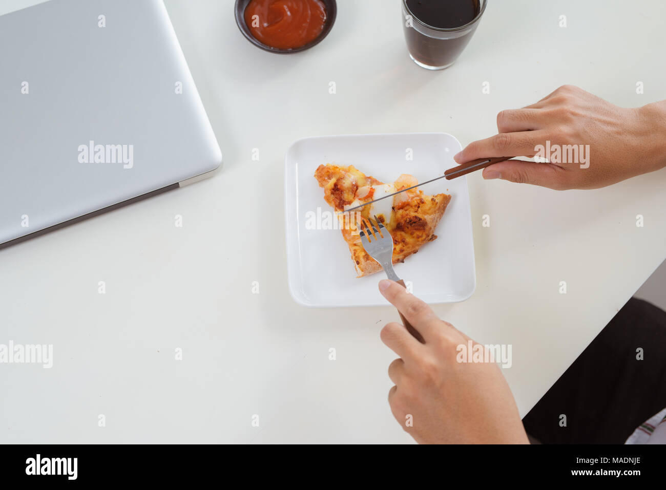 close up man hand eating pizza while working in laptop computer Stock ...
