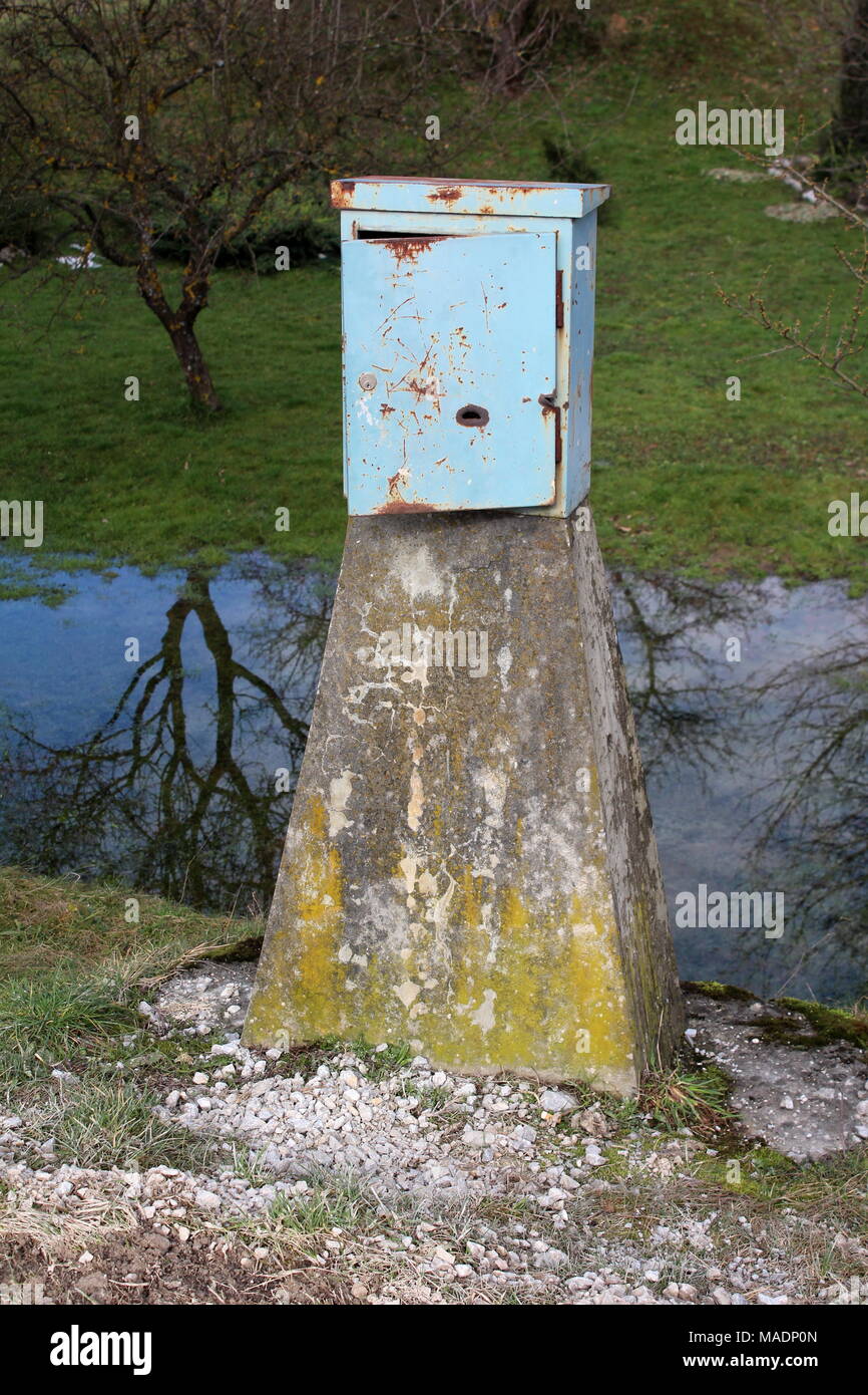 Rusted metal electrical junction box with open door mounted on concrete ...