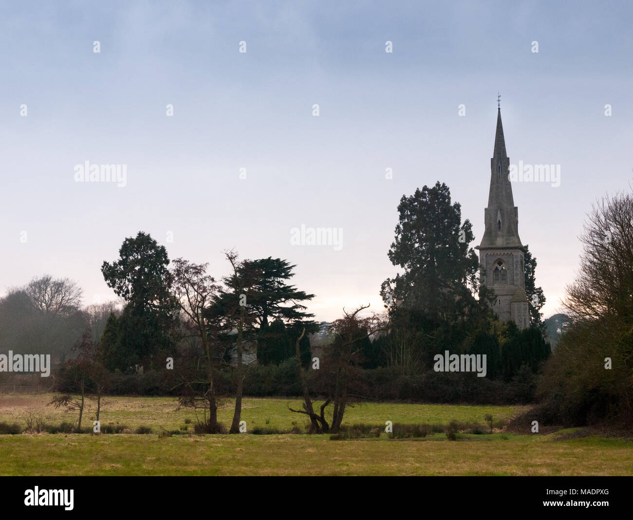 Mistley christian church as seen from over a field with trees in spring ...