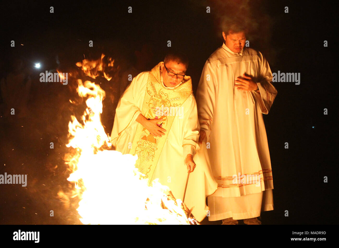 Paranaque, Philippines. 31st Mar, 2018. A priest gets a new flame to ...