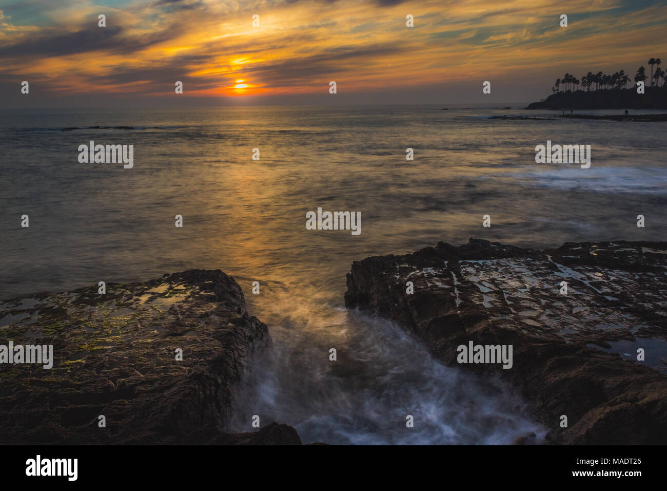 Beautiful coastal view of a colorful sky at sunset with waves crashing ...
