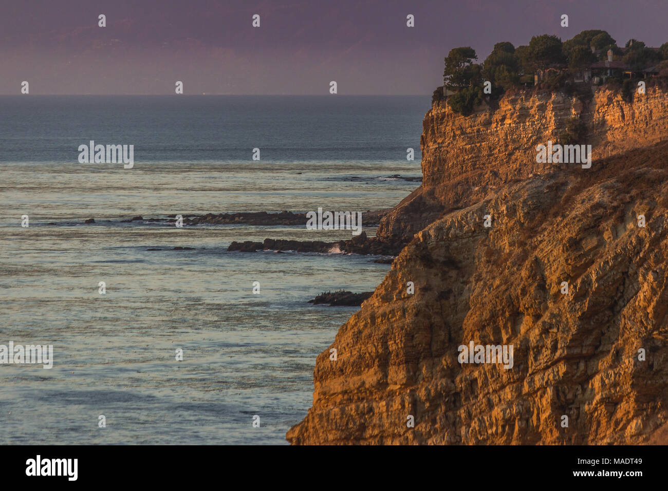 Colorful coastal view of tall cliffs and ocean at sunset with layers of ...