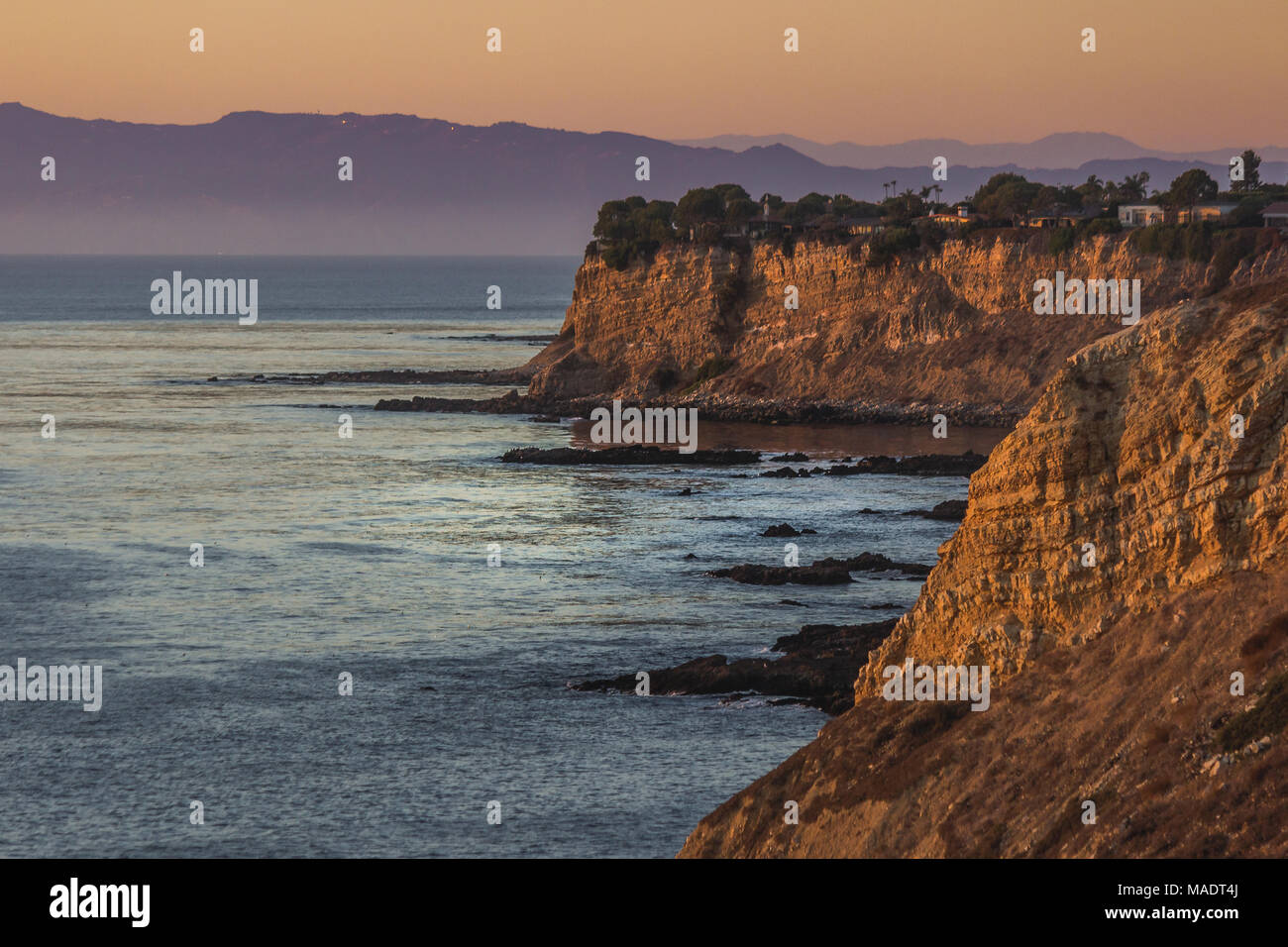 Colorful coastal view of tall cliffs and ocean at sunset with layers of ...