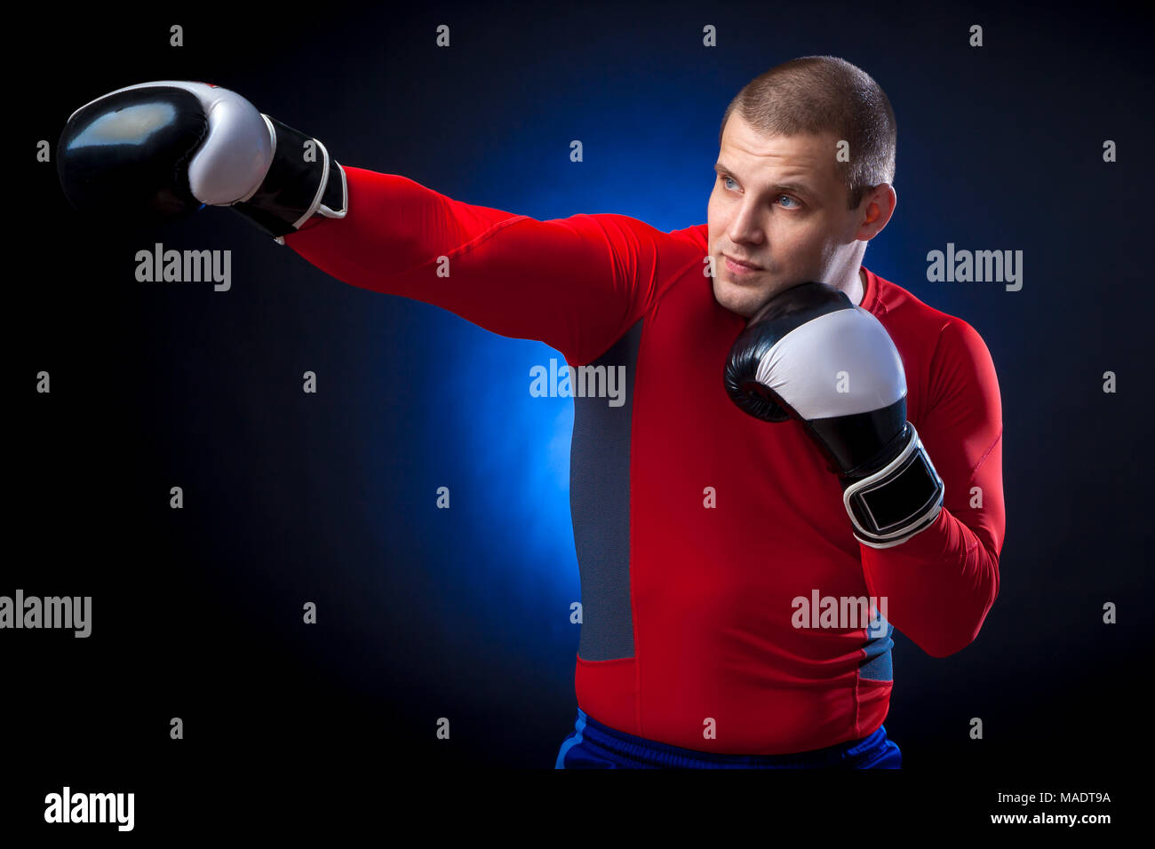 A strong dark-haired sportman boxer in a red sports wear rush guard and ...