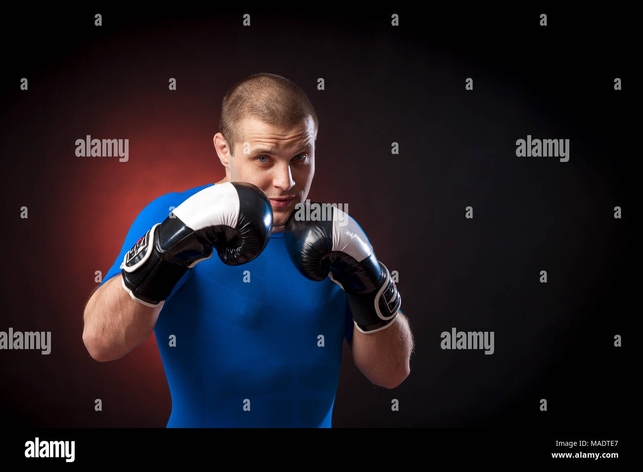 A strong dark-haired sportman boxer in a blue sports wear rush guard ...
