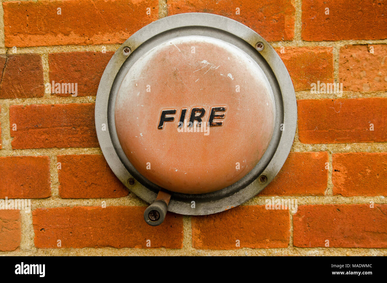 An old fashioned hand operated fire alarm bell fixed the brick wall of ...