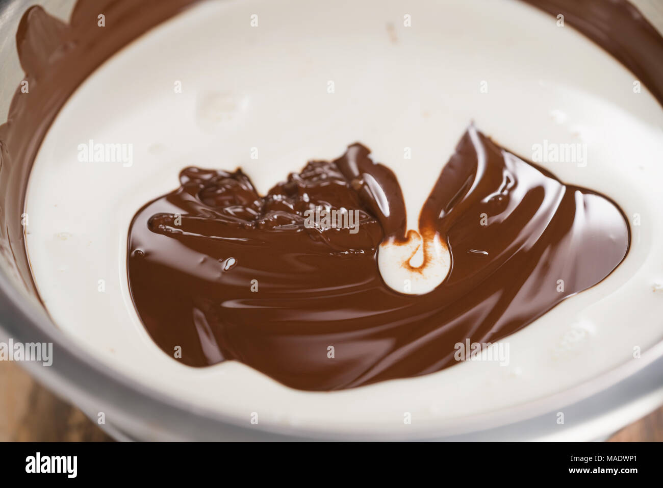 adding cream into melted chocolate, cooking process Stock Photo - Alamy