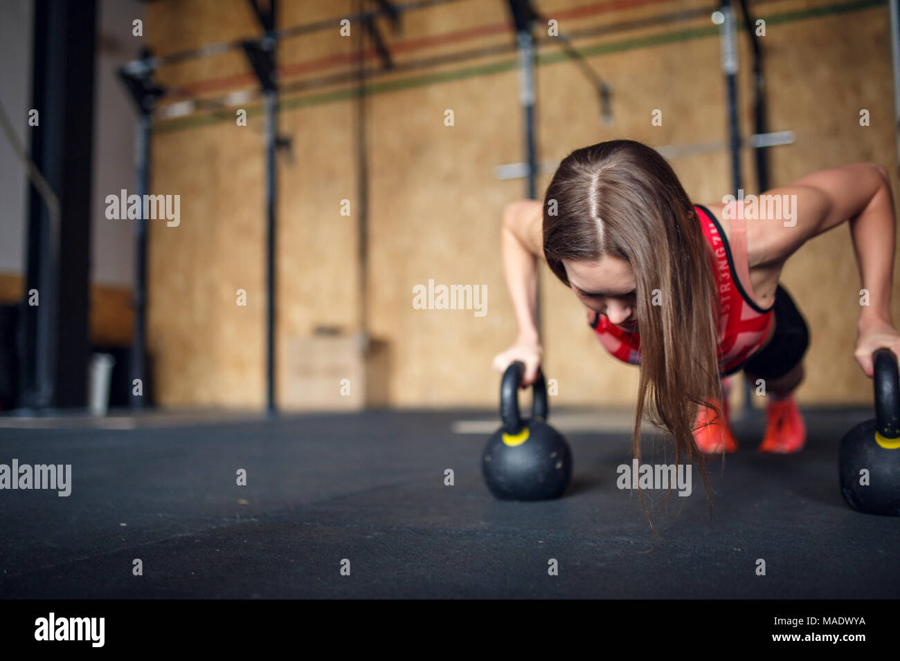 Image of spotswoman doing horizontal push-ups with kettlebells in gym ...
