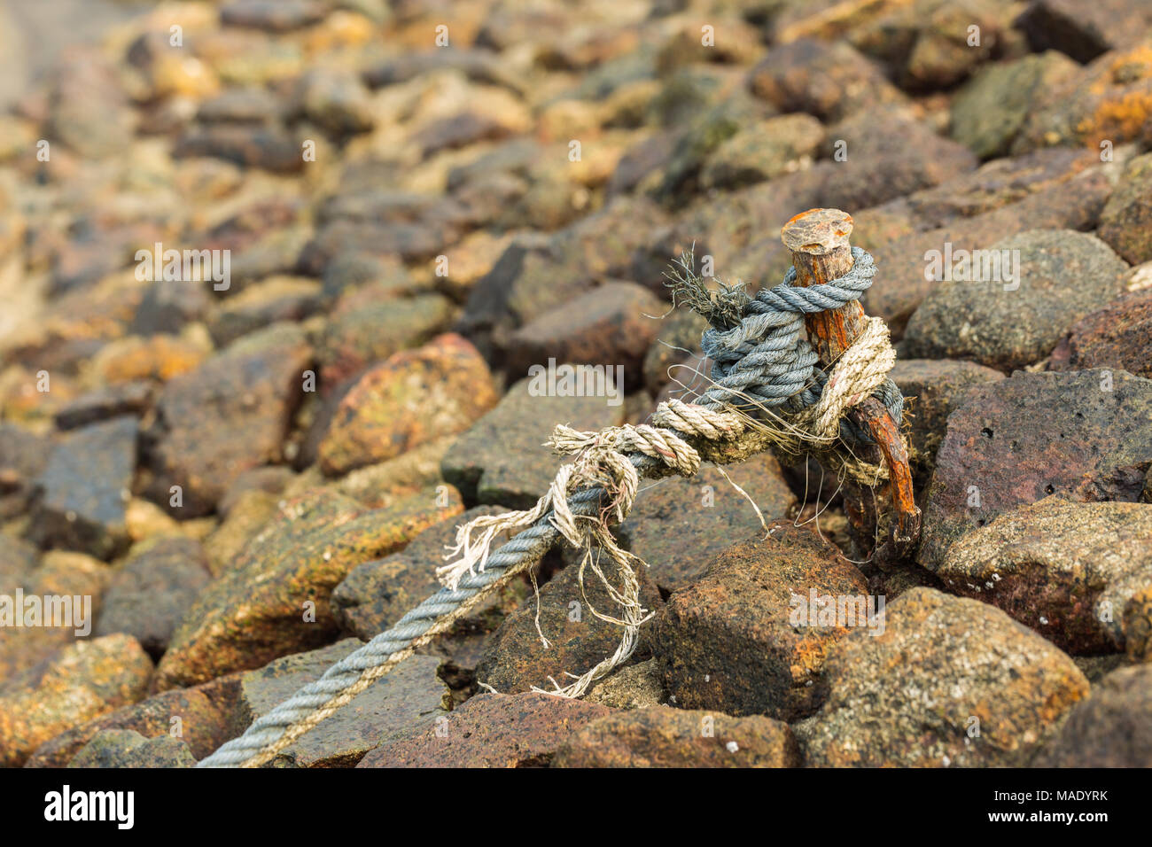 old rope tied with rusty iron on rock Stock Photo - Alamy