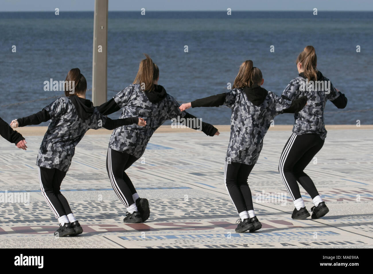 A troupe of young female dancers, all dressed in matching black and ...
